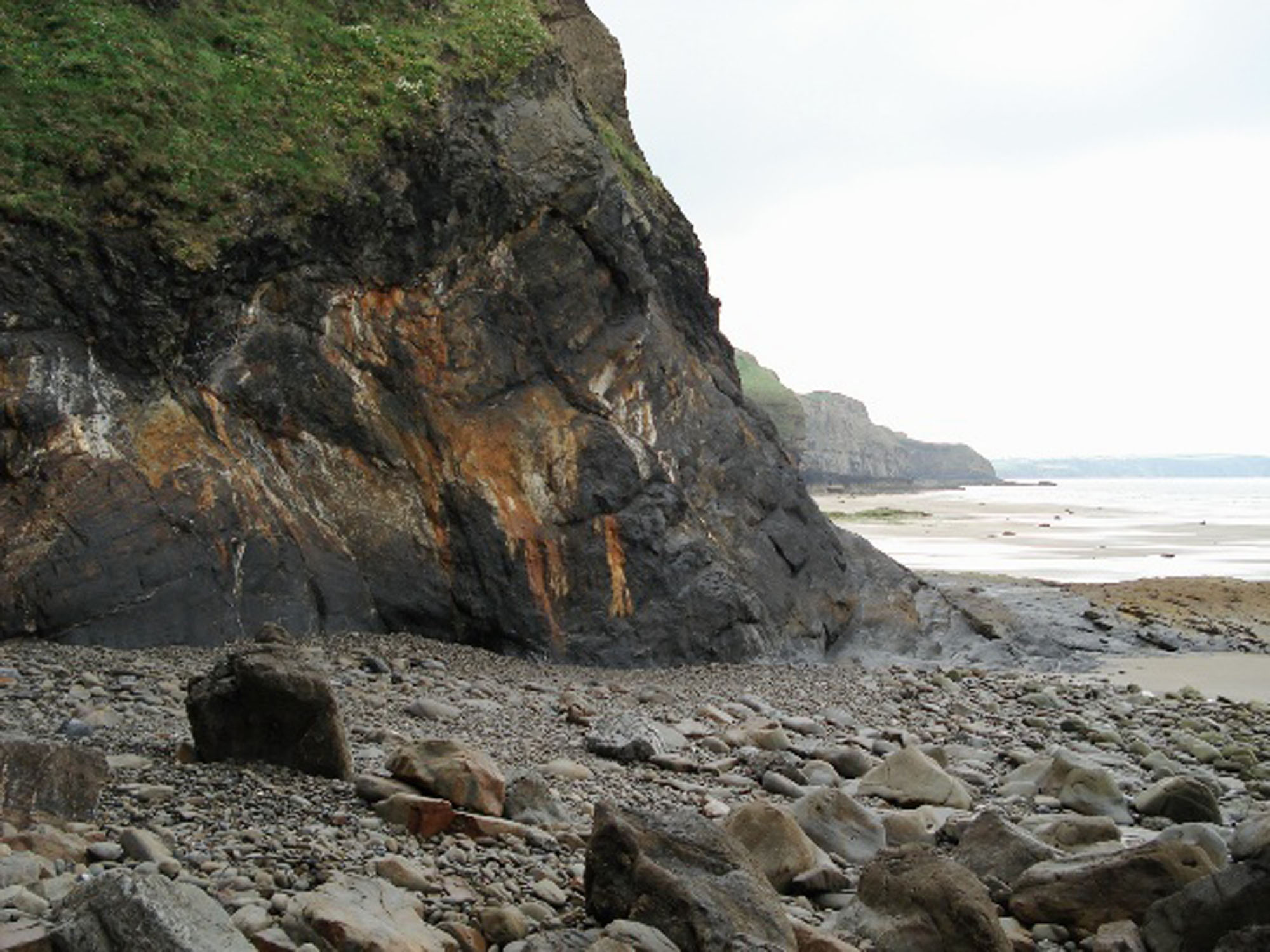 Shale cliff with cobbles below, some are shale – UK Fossil Collecting